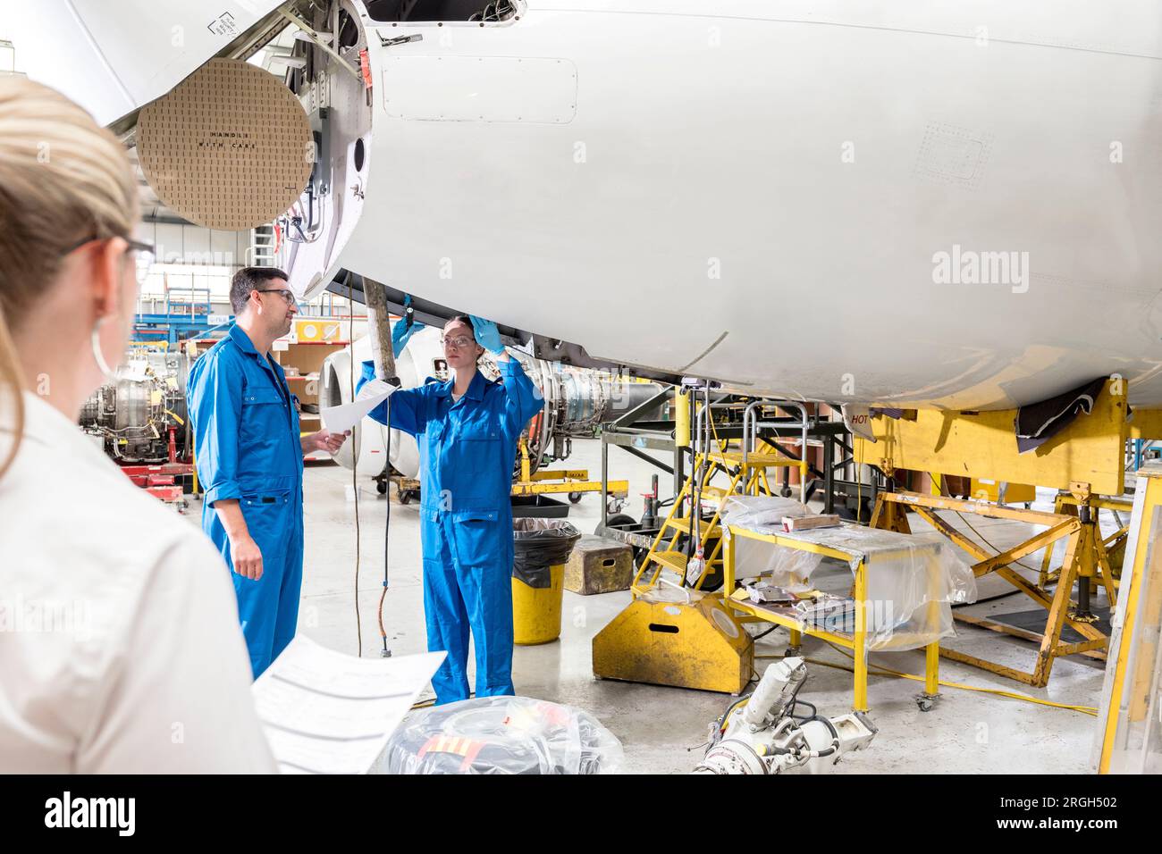 Workers under airplane in hangar Stock Photo - Alamy