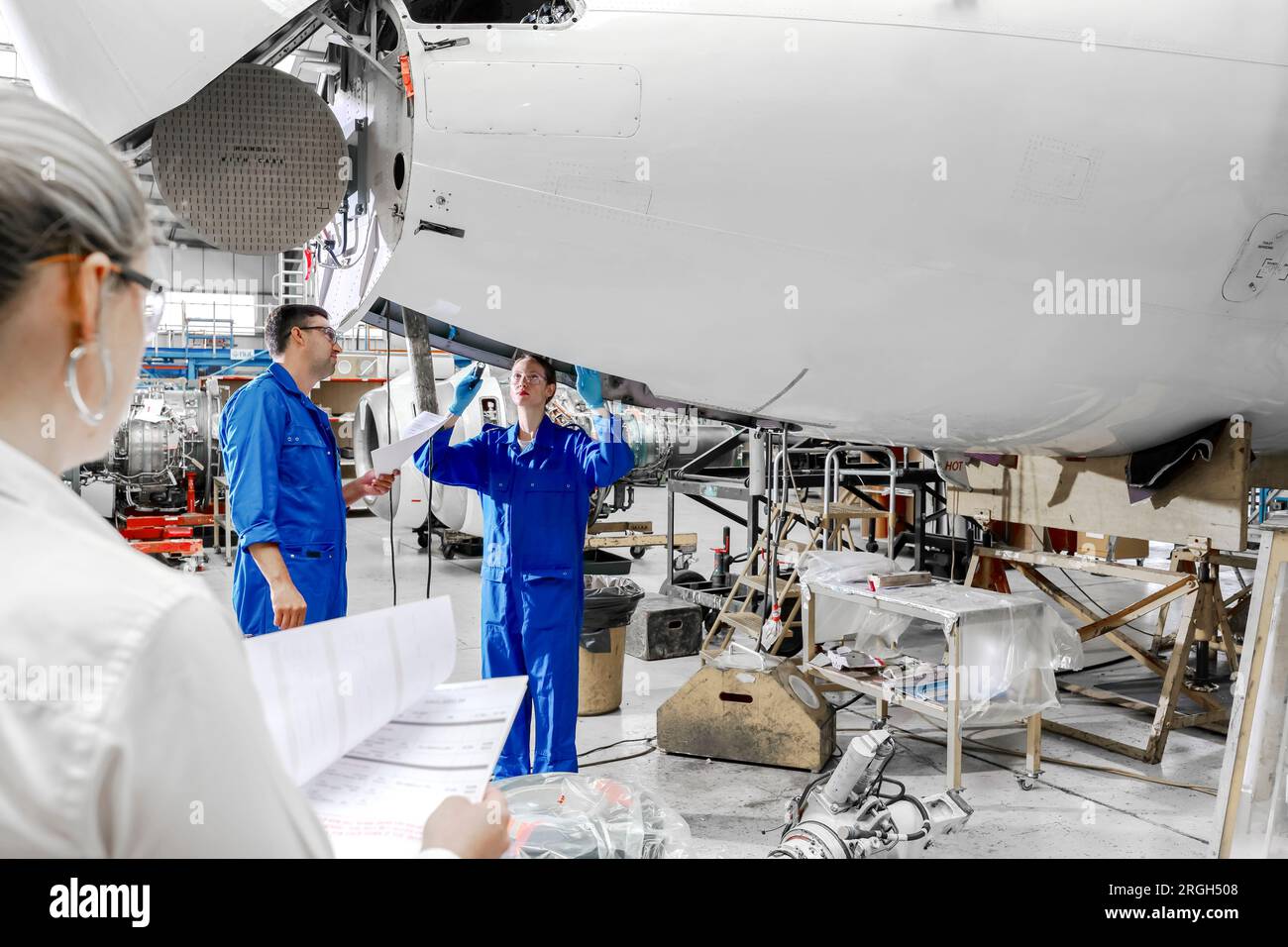 Workers under airplane in hangar Stock Photo - Alamy