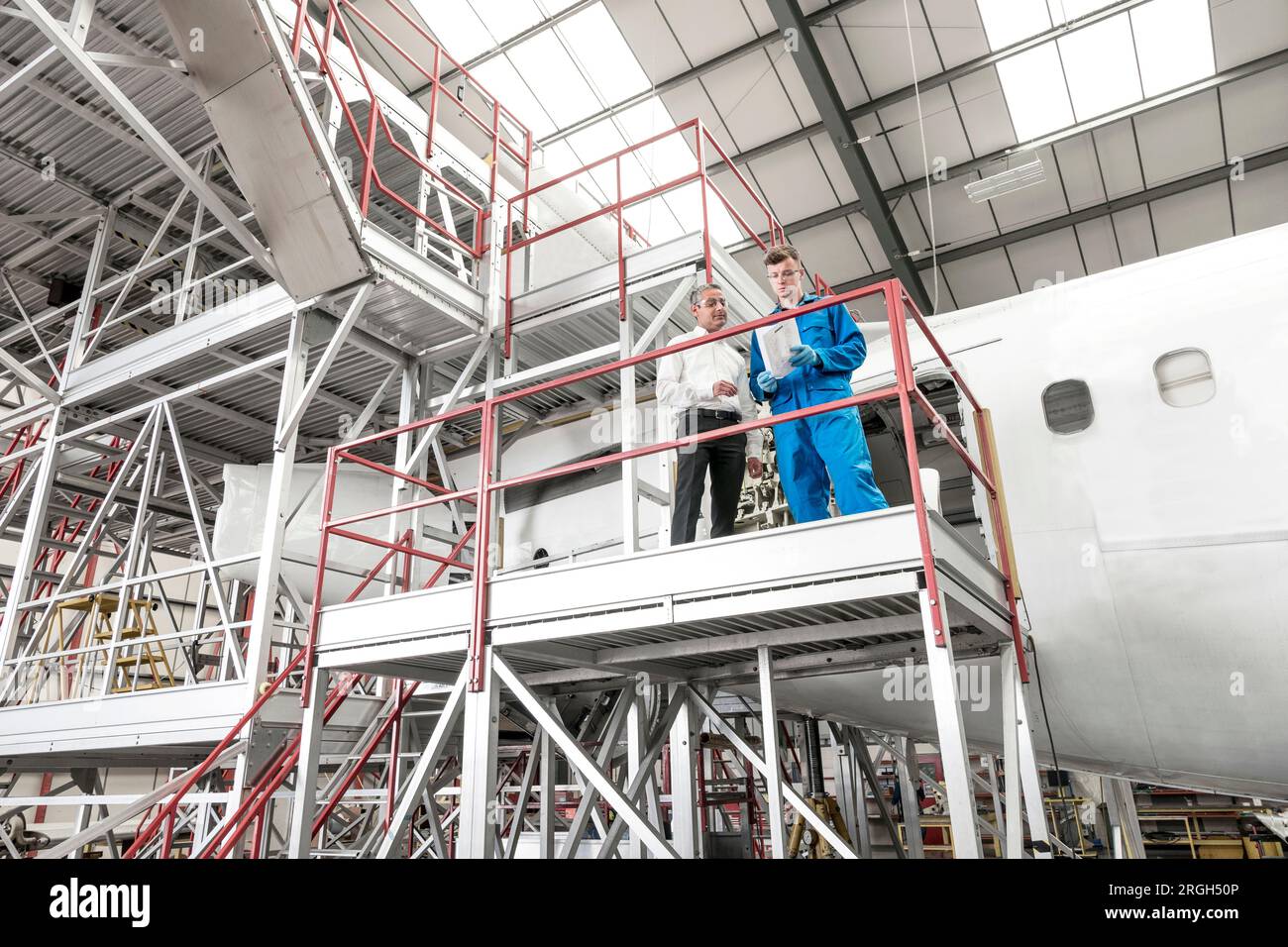 Men reading paperwork in airplane hangar Stock Photo - Alamy