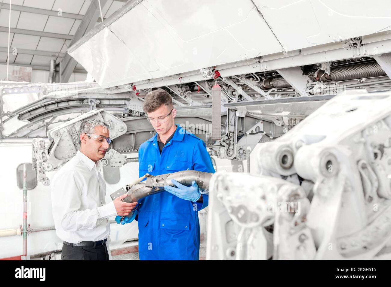 Men examining pipe in airplane hangar Stock Photo - Alamy