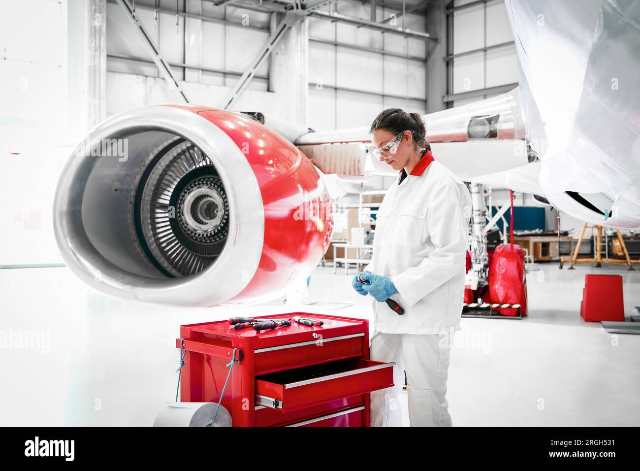 Woman holding tools by airplane engine by hangar Stock Photo - Alamy