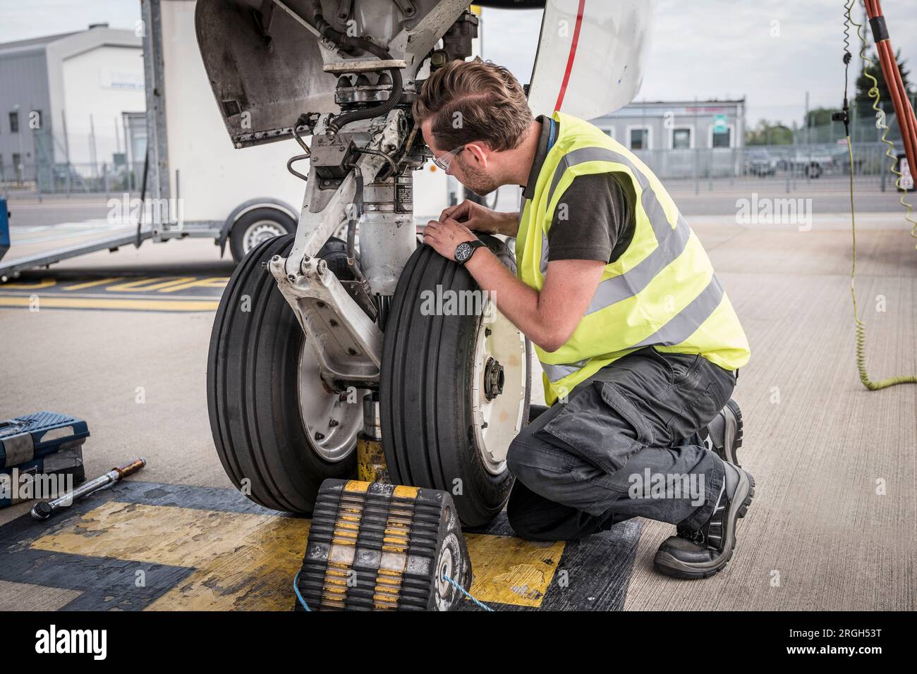 Man working on airplane wheel Stock Photo - Alamy