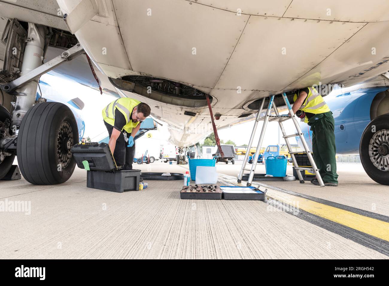 Men working underneath airplane Stock Photo - Alamy