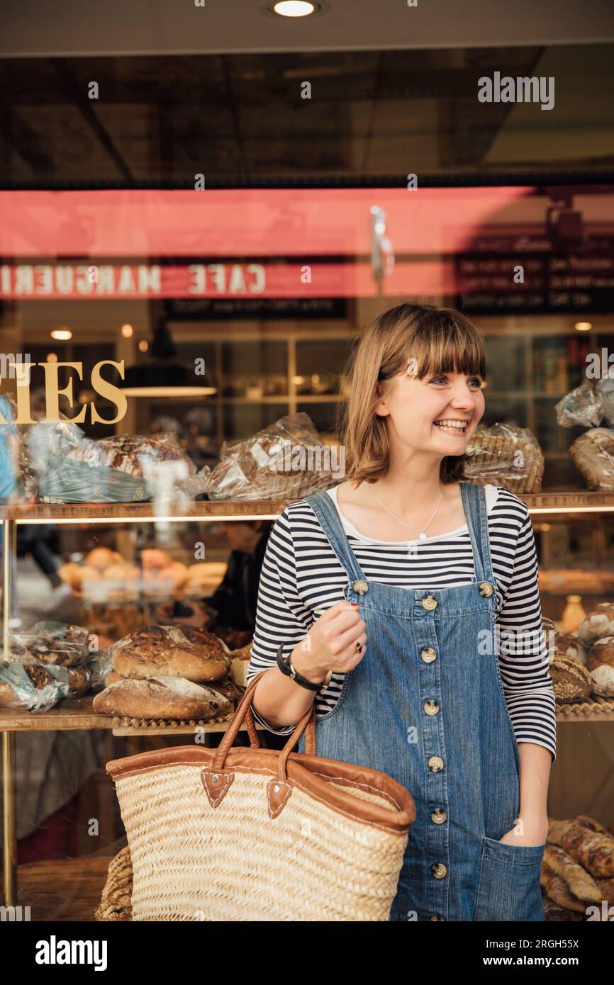 Smiling young woman outside bakery Stock Photo - Alamy