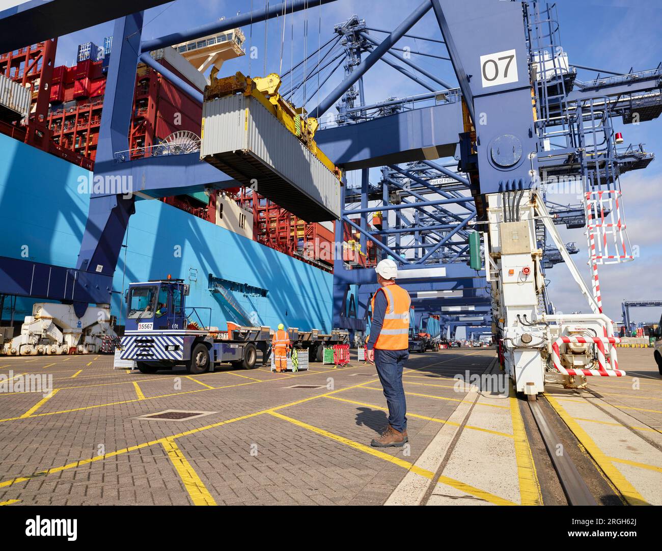 Crane lowering cargo container onto truck at Port of Felixstowe ...