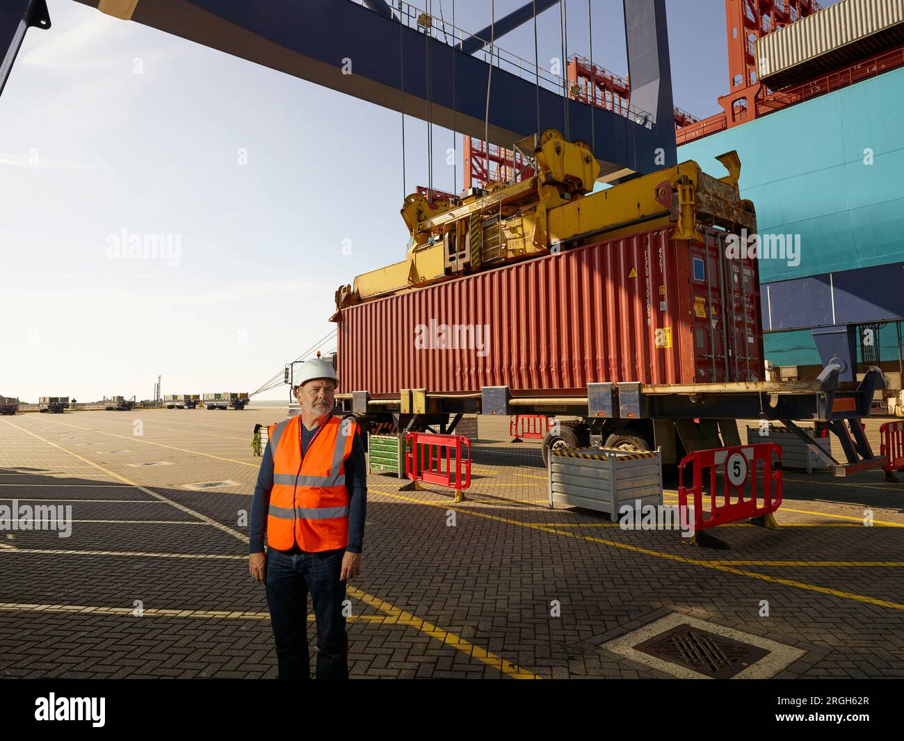 Dock worker by cargo container and truck at Port of Felixstowe, England ...