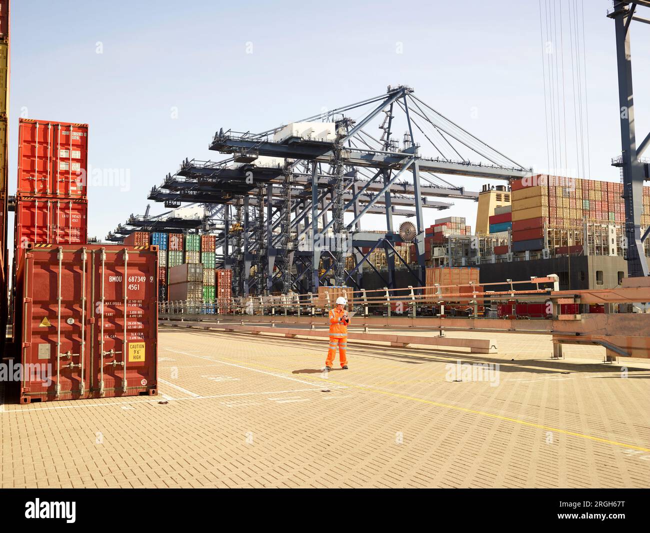 Dock worker examining stack of cargo containers at Port of Felixstowe ...