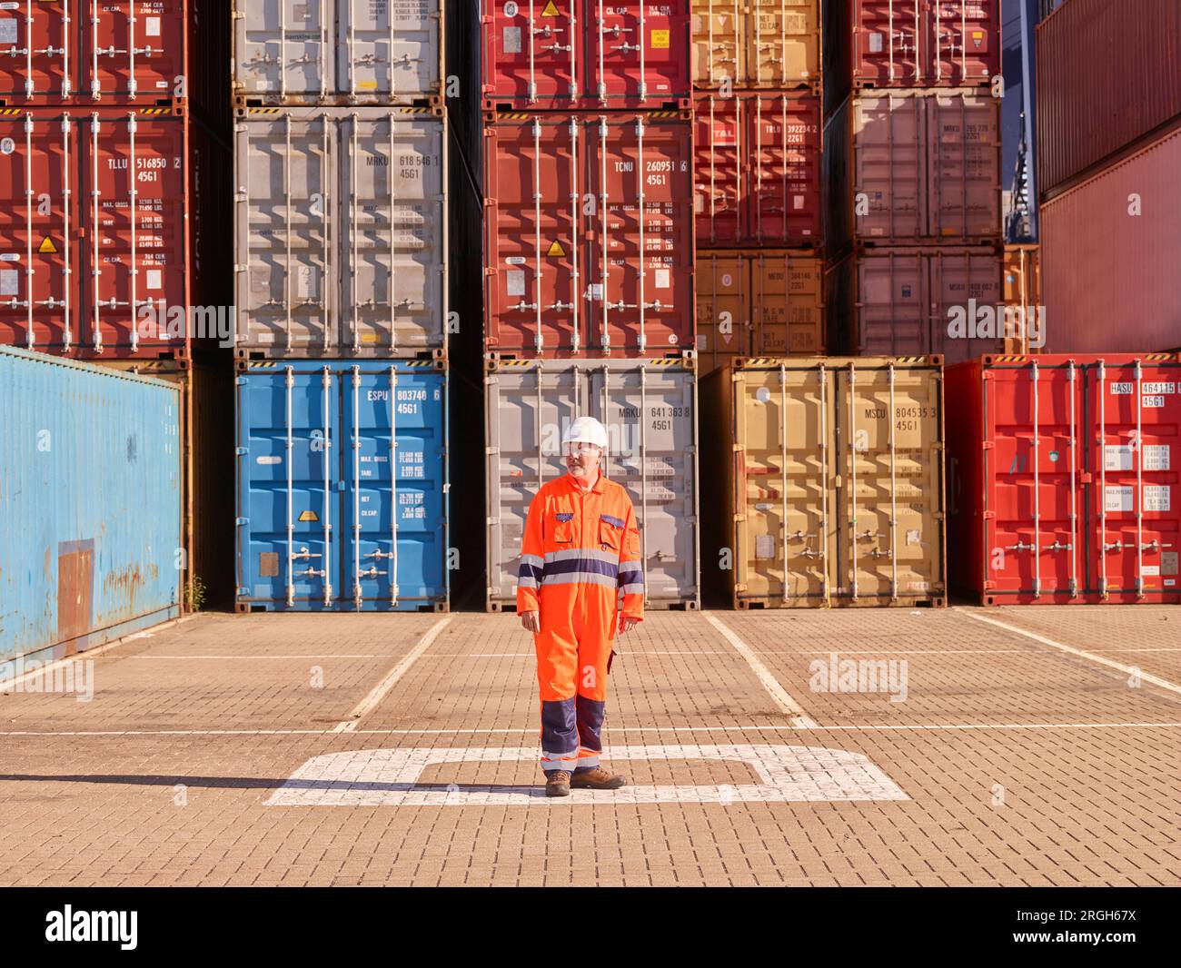 Dock worker by stack of cargo containers Stock Photo - Alamy