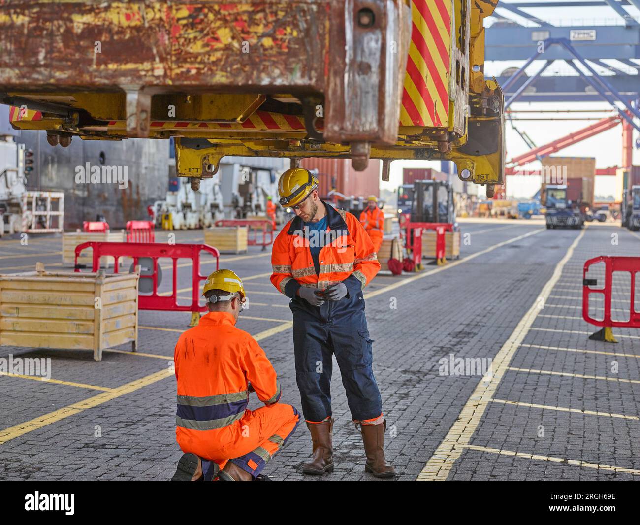 Dock workers inspecting mechanical grabber of crane Stock Photo - Alamy