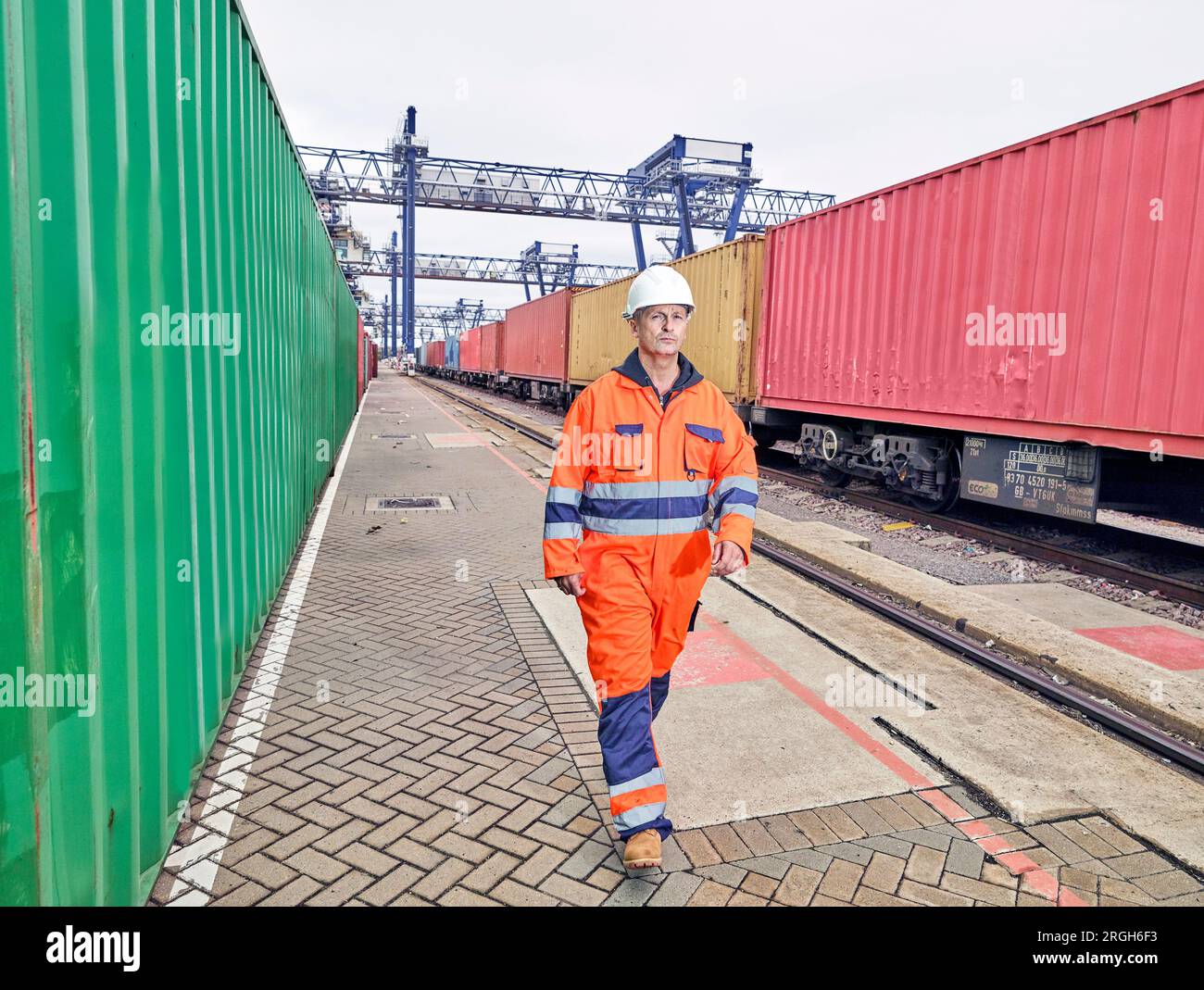 Dock worker walking by cargo train Stock Photo - Alamy