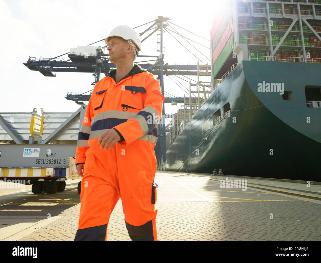Dock worker walking beside cargo ship at Port of Felixstowe, England ...