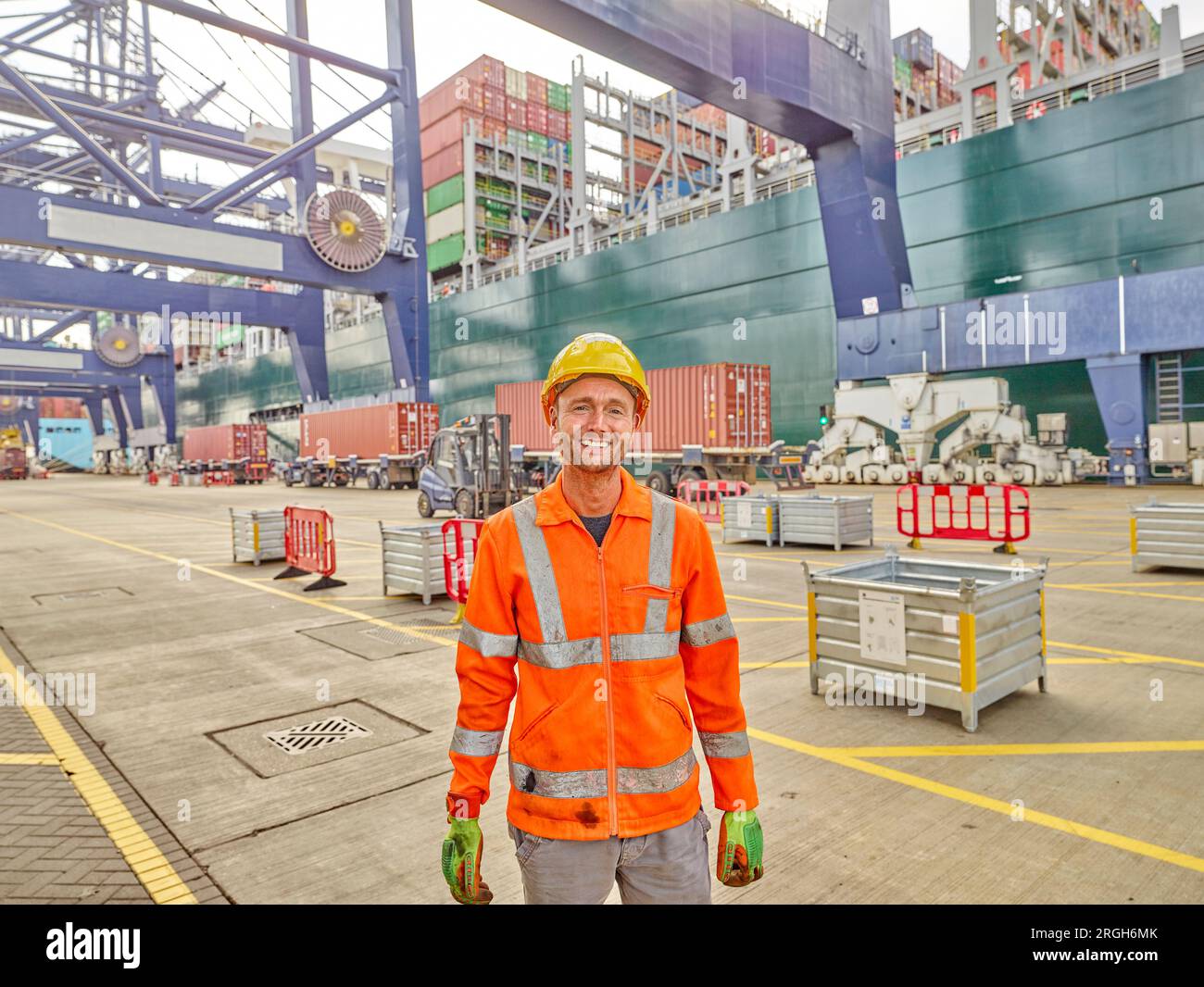 Smiling dock worker in reflective clothing and hard hat Stock Photo - Alamy