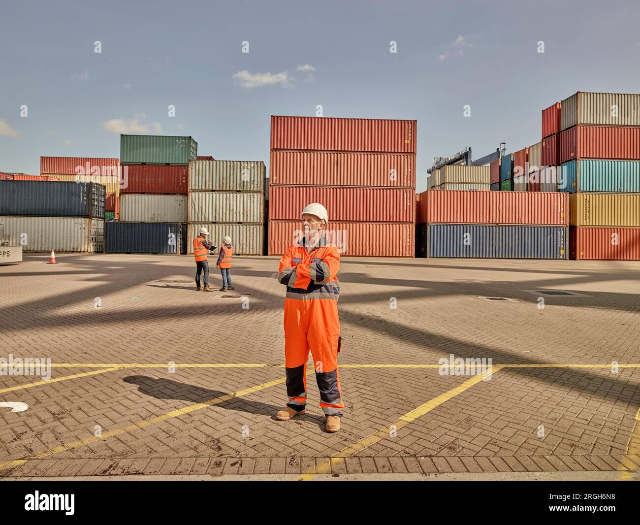 Dock worker in reflective overalls by cargo containers Stock Photo - Alamy
