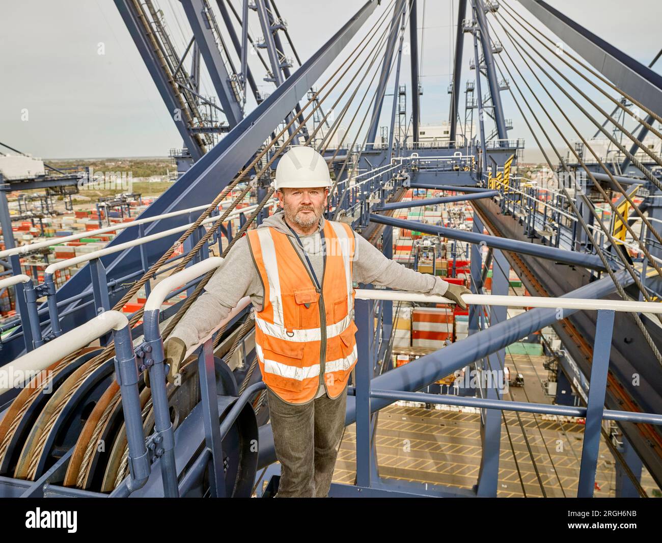 Dock worker by railing of crane Stock Photo - Alamy