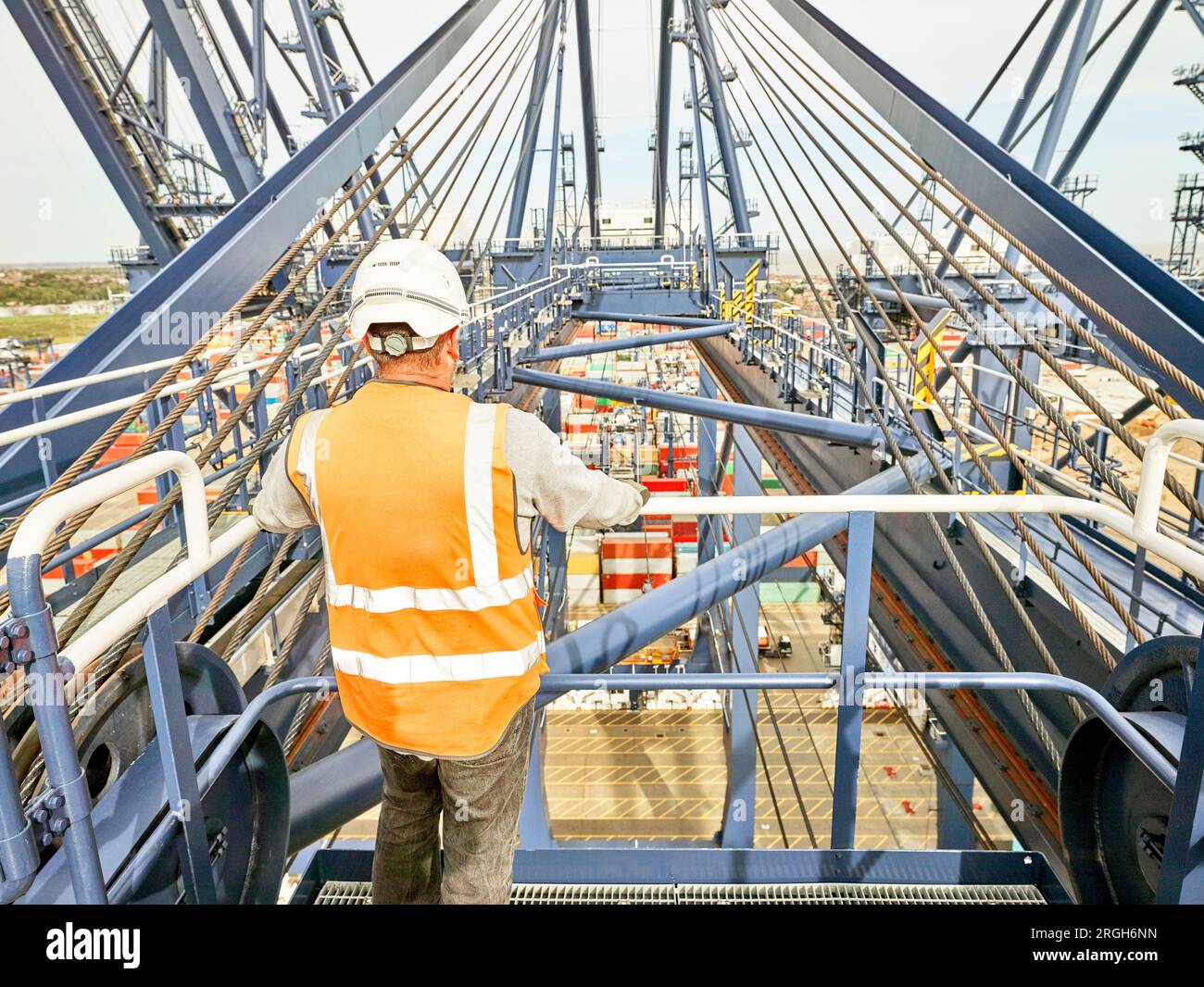 Dock worker by railing of crane Stock Photo - Alamy