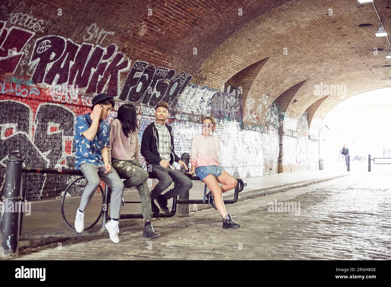Teenage friends sitting on gate in tunnel Stock Photo - Alamy