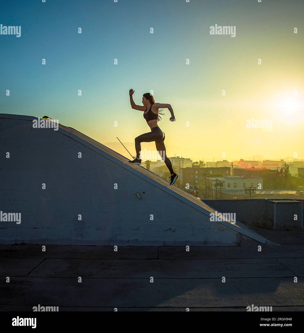 Young woman running on rooftop ramp Stock Photo - Alamy