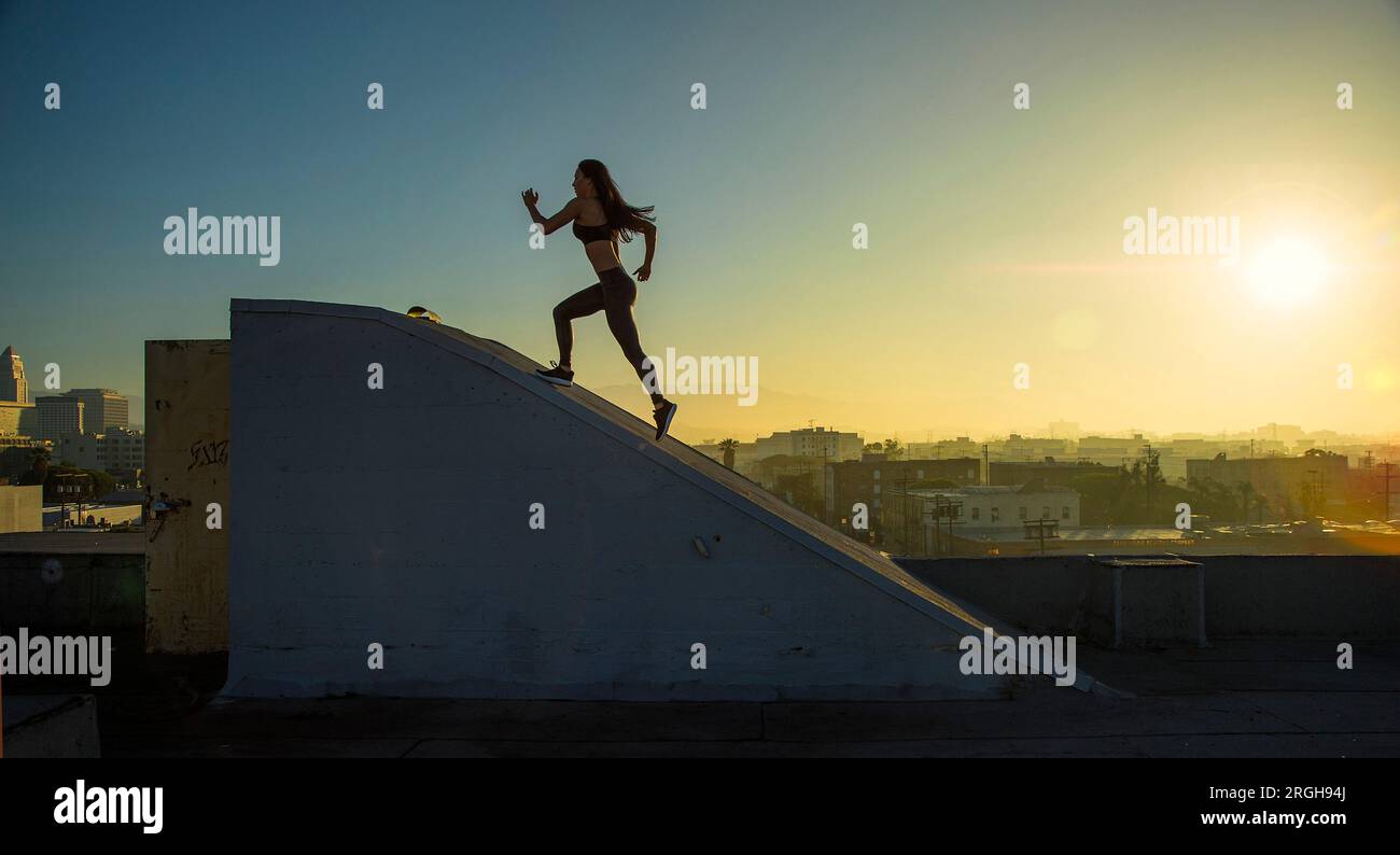 Young woman running on rooftop ramp Stock Photo - Alamy
