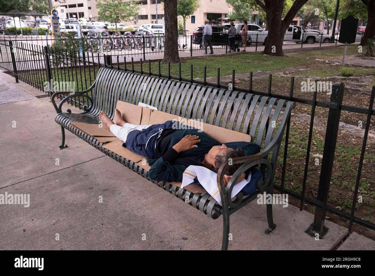 A man rests on a public park bench across from the Texas Capitol at ...