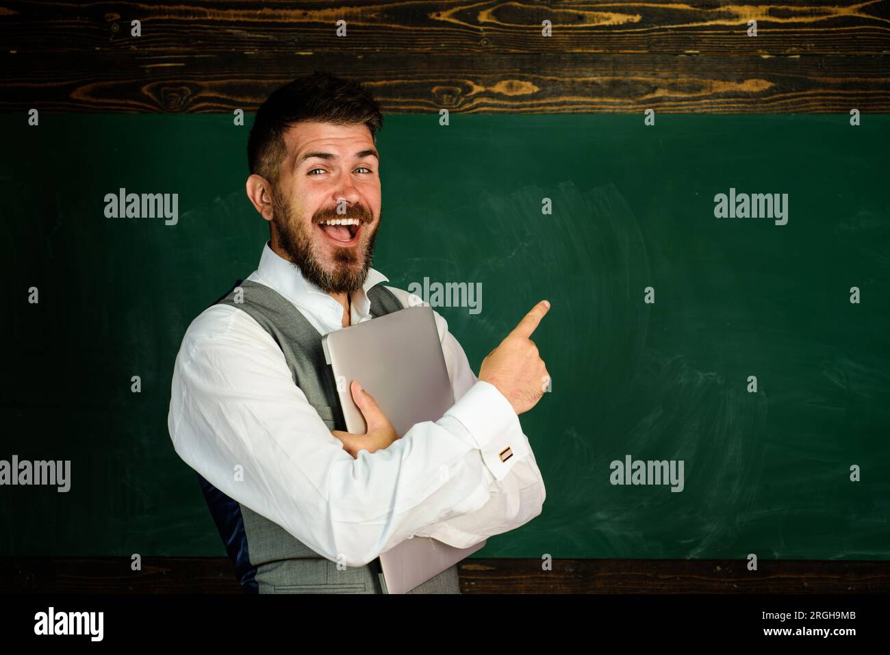 Back to school. Happy teacher near chalkboard pointing at copy space ...