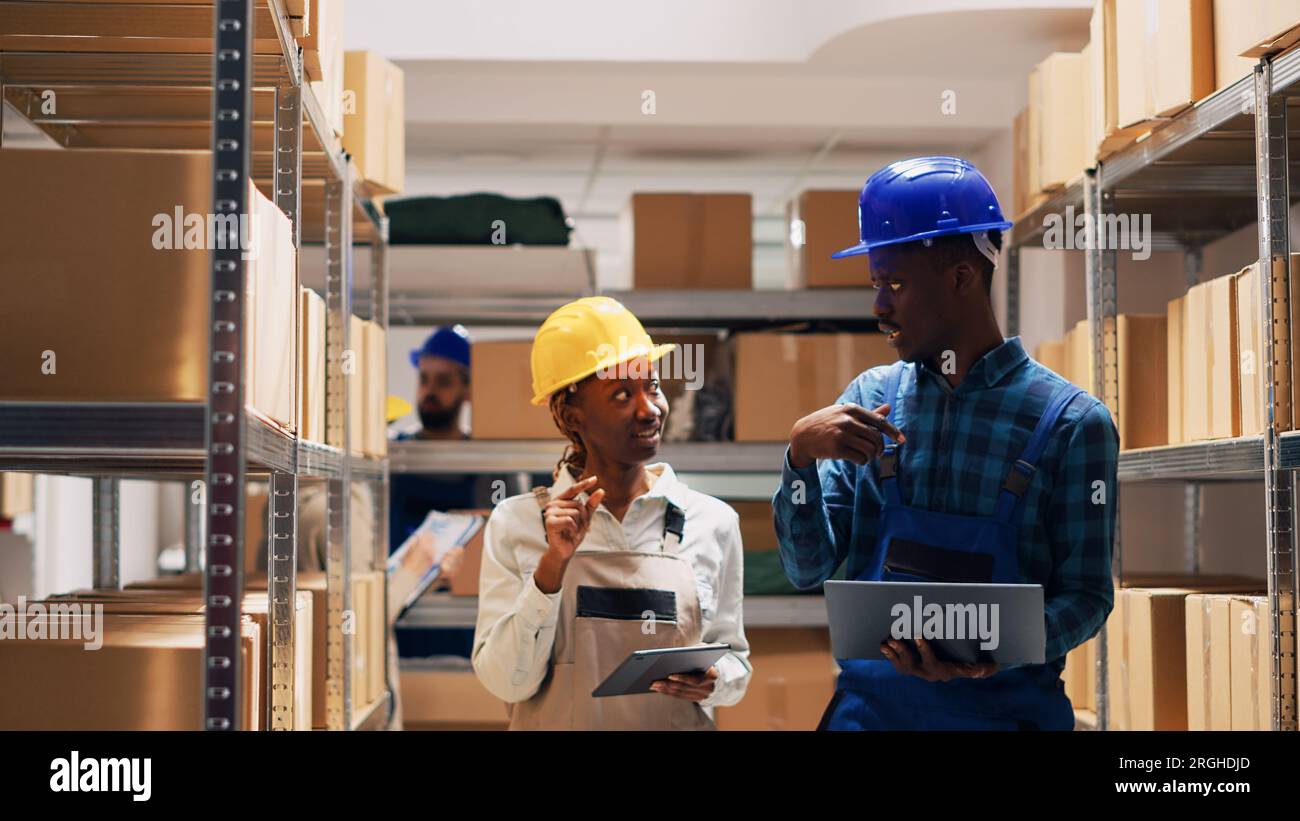 African american team counting warehouse goods on racks and planning ...