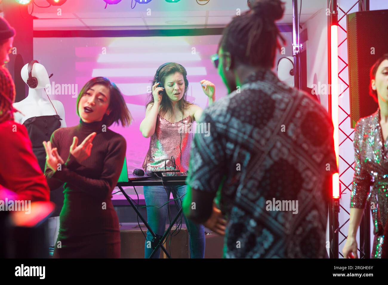 Woman dj in headphones performing using electronic music mixing station ...