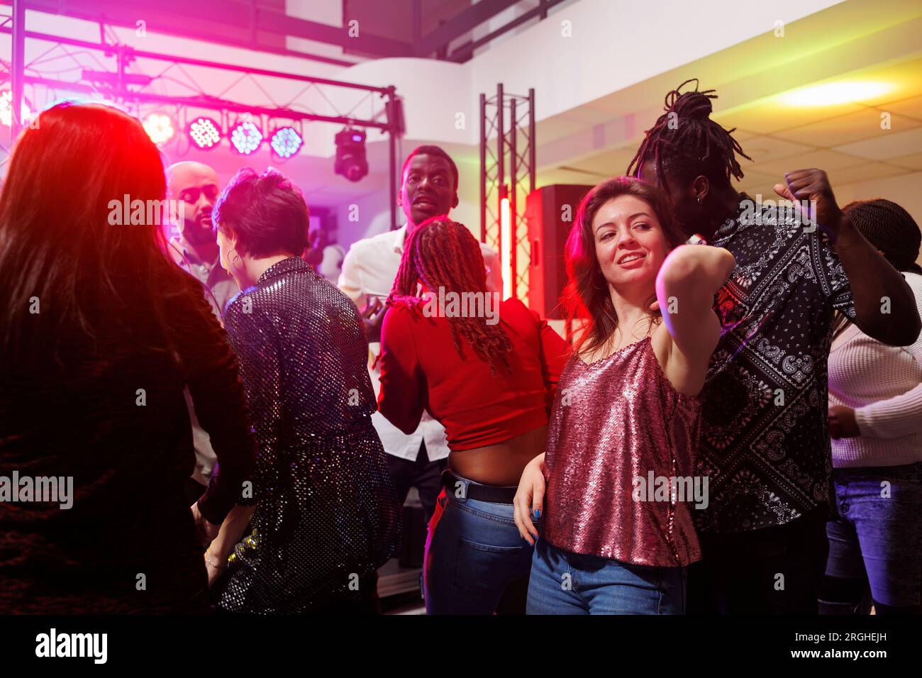 Multiracial couple dancing together while partying in crowded nightclub ...
