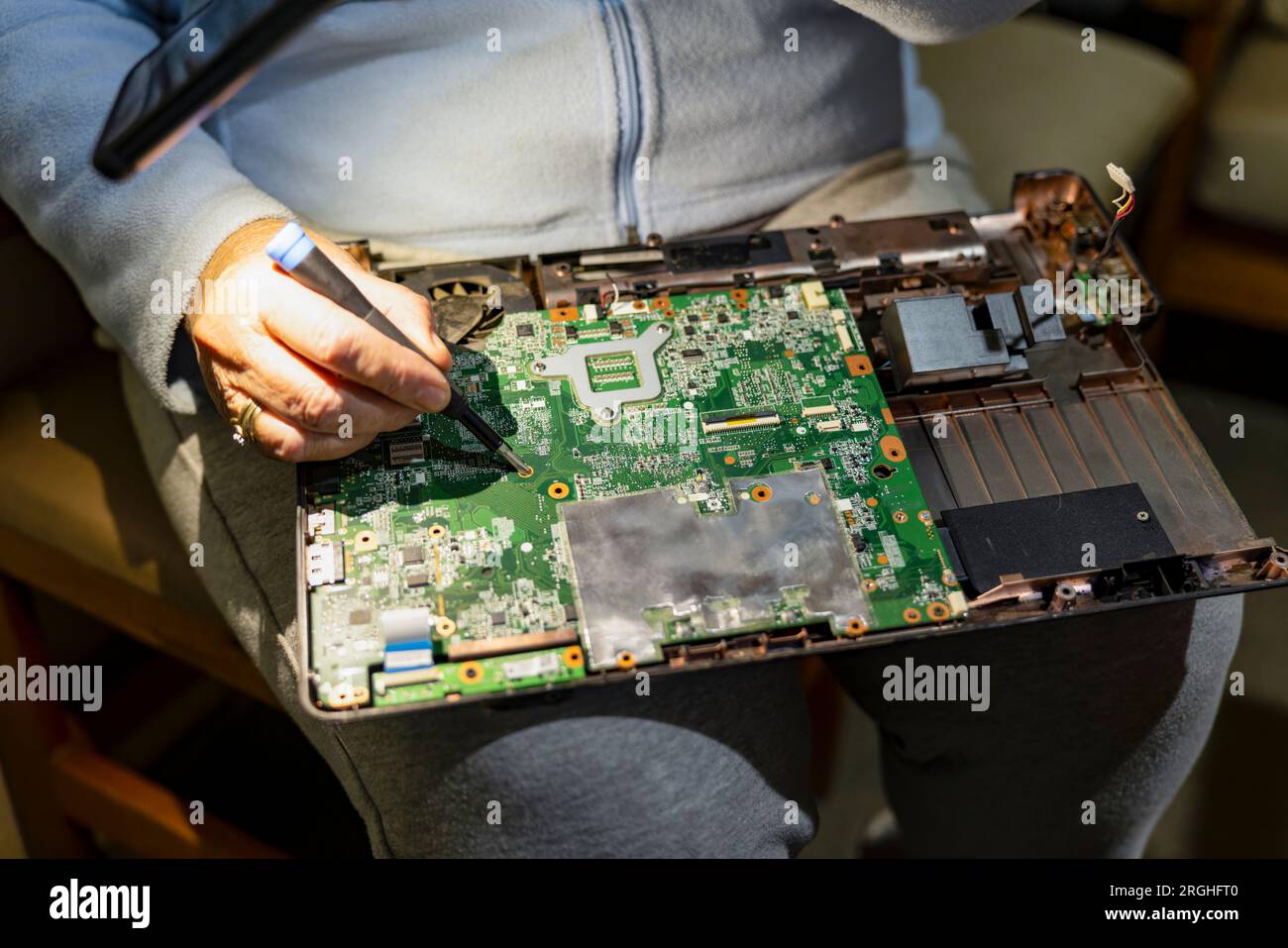 computer repairs, old woman in her seventies repairing her laptop ...