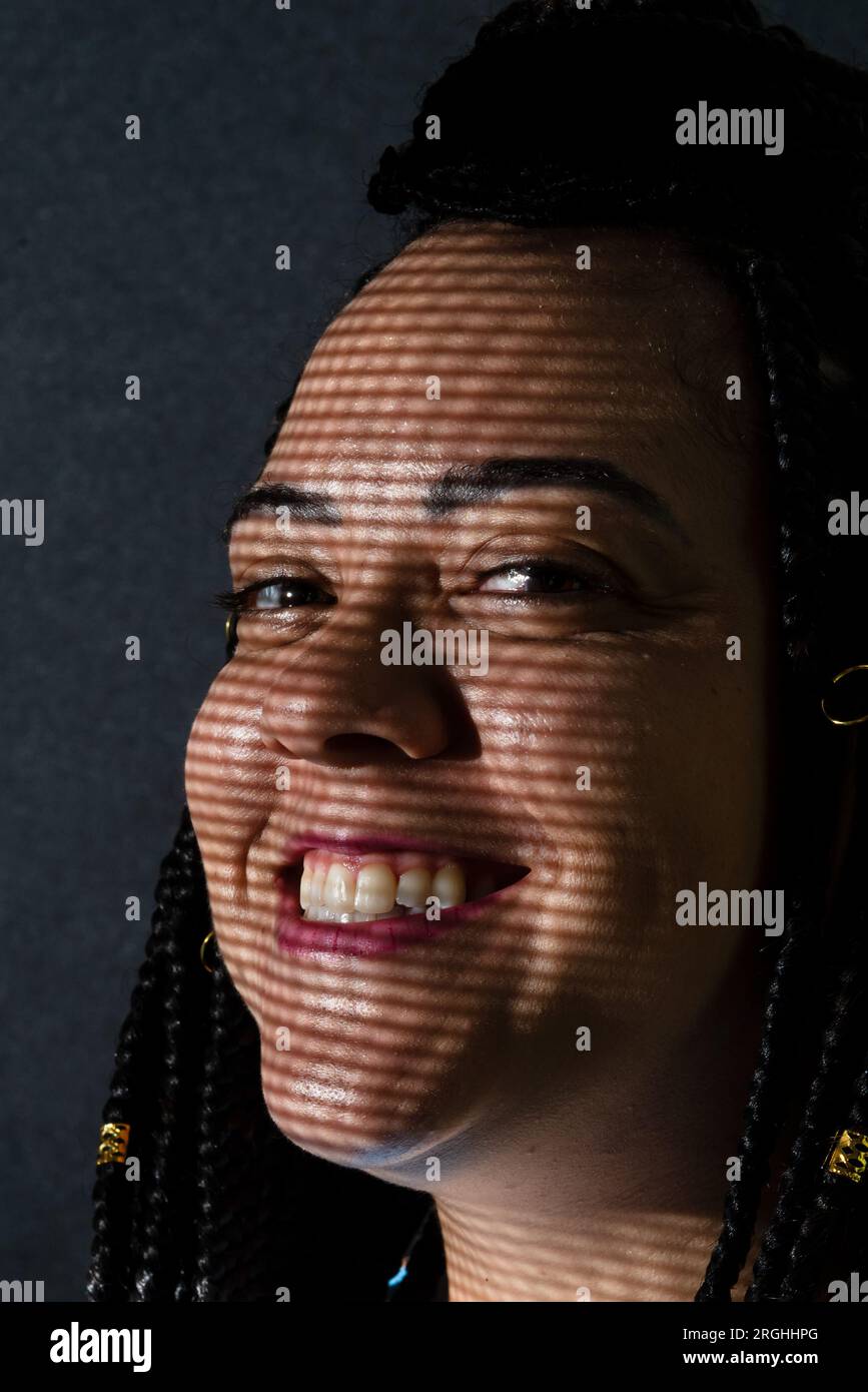 Close-up portrait of a beautiful woman with braids in her hair and geometric shadows on her face ...