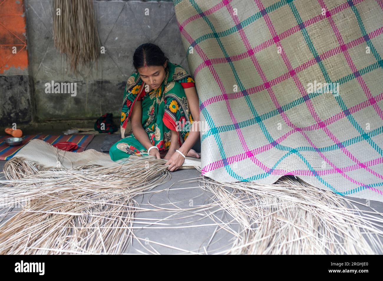 A woman weaves traditional shitol pati (cool mat) at her home in Hailakathi village of ...