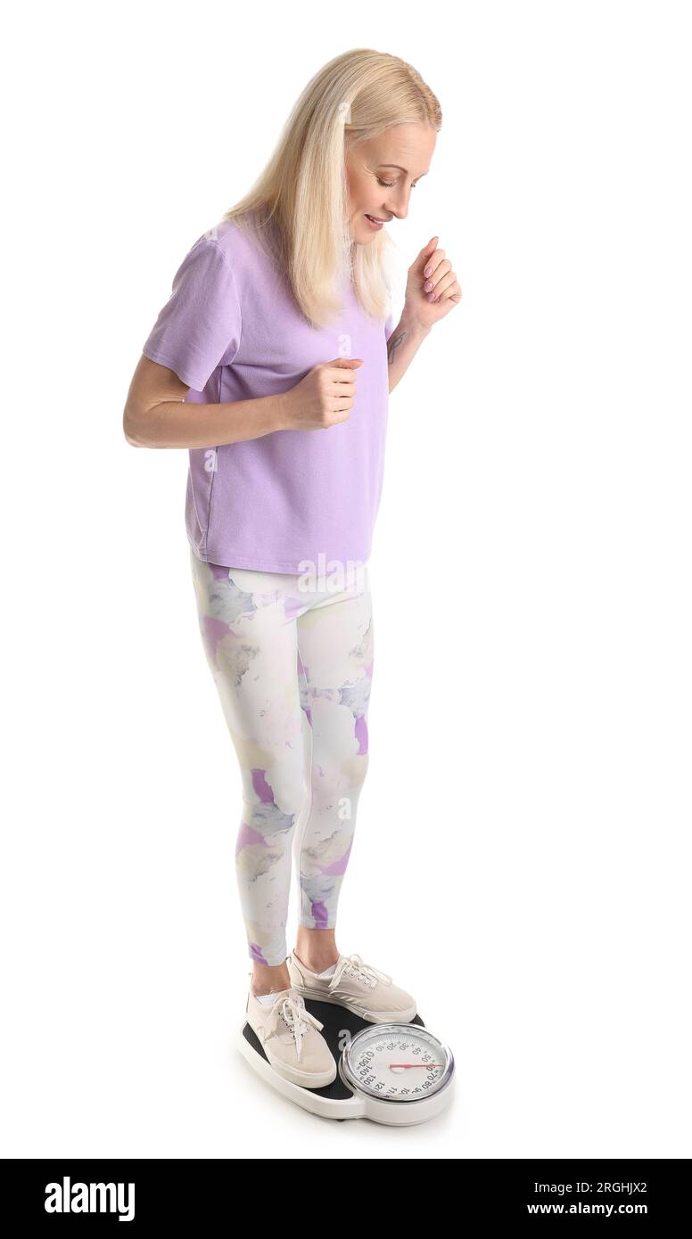 Mature woman measuring her weight on scales against white background ...