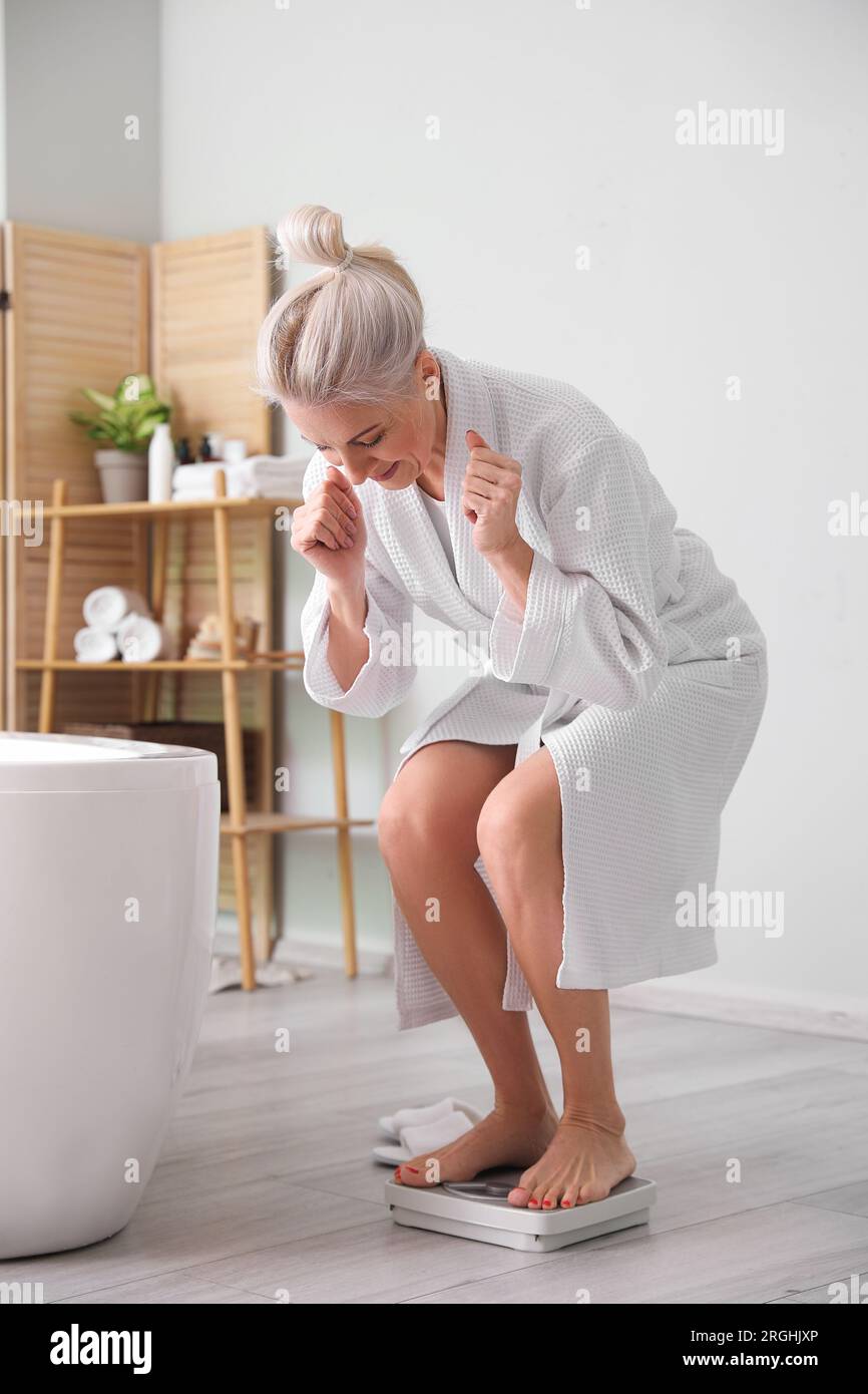 Mature woman measuring her weight on scales in bathroom Stock Photo - Alamy