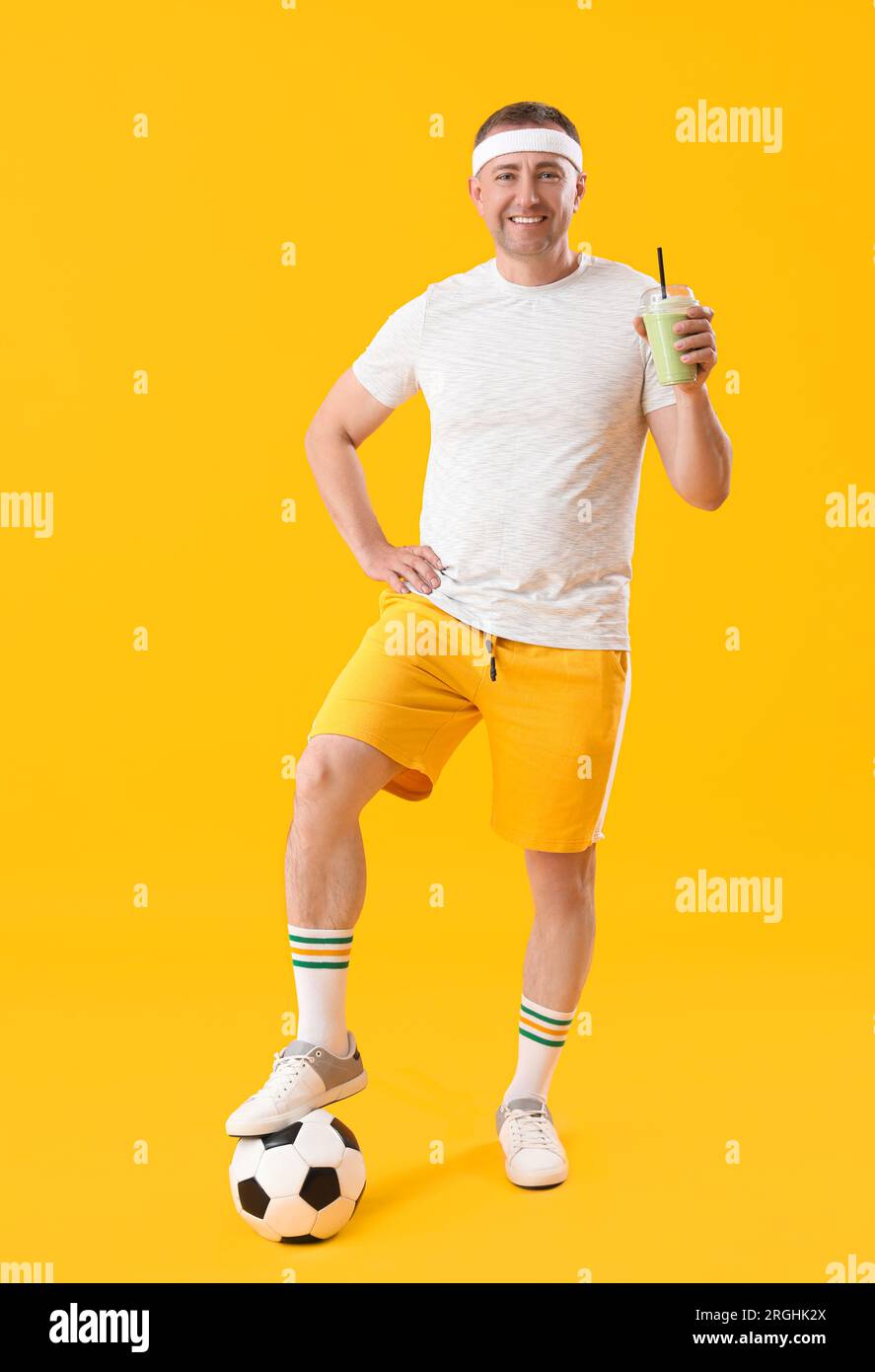Sporty mature man with glass of vegetable smoothie and soccer ball on ...