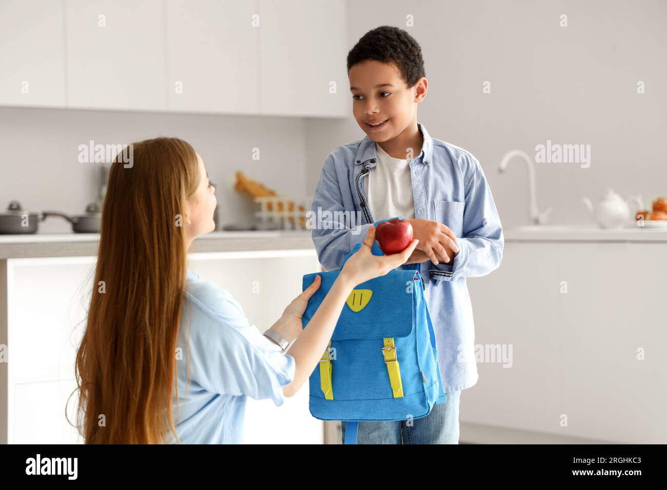 Mother giving apple to little schoolboy in kitchen Stock Photo - Alamy