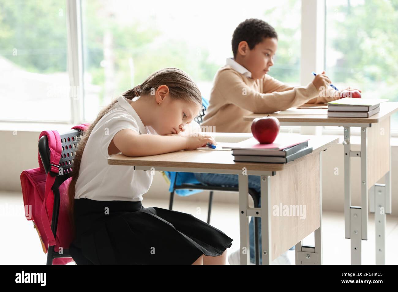 Little students sitting at desks in classroom Stock Photo - Alamy
