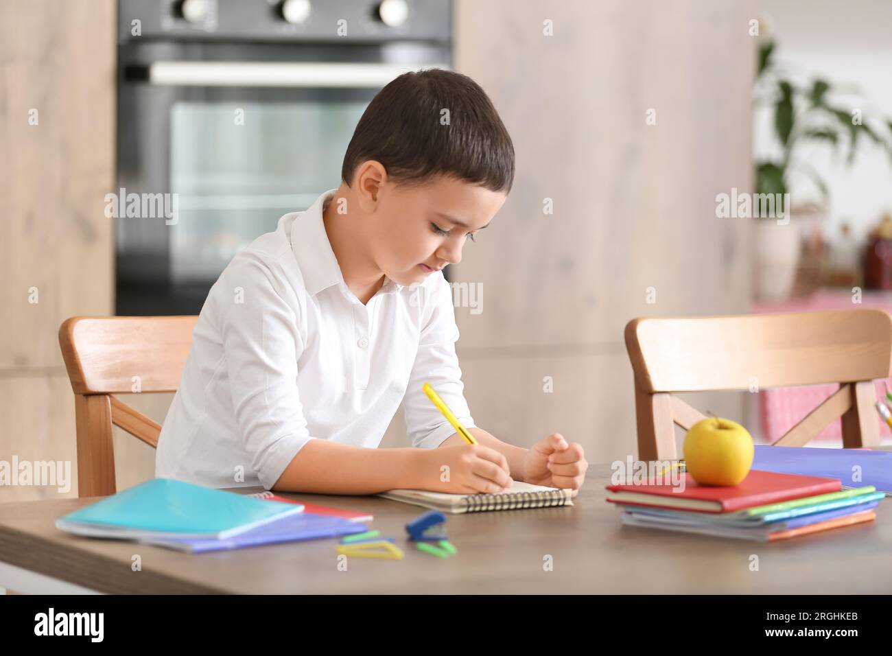 Cute little boy doing homework in kitchen Stock Photo - Alamy