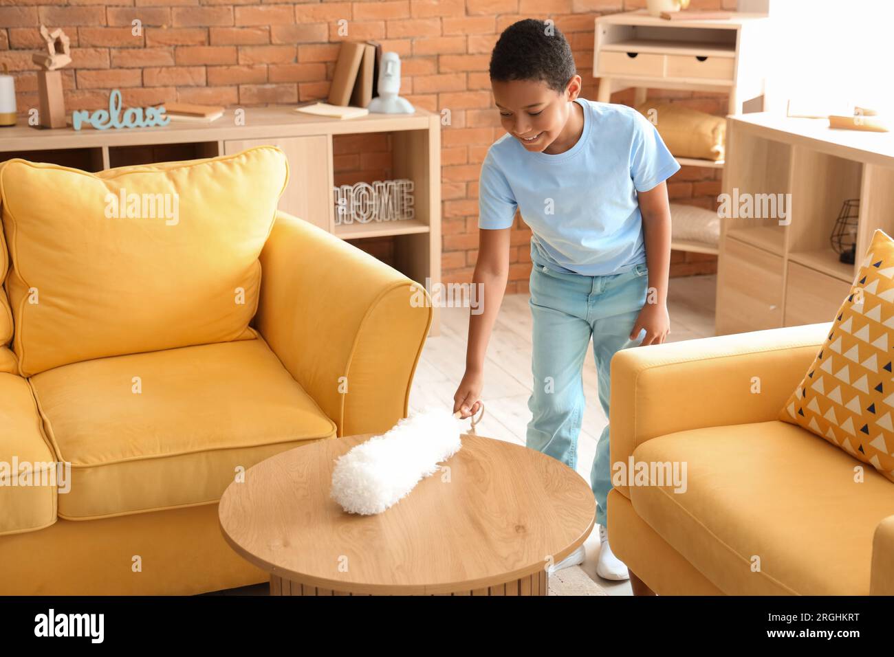 Cute little African-American boy cleaning table with duster in living room Stock Photo - Alamy