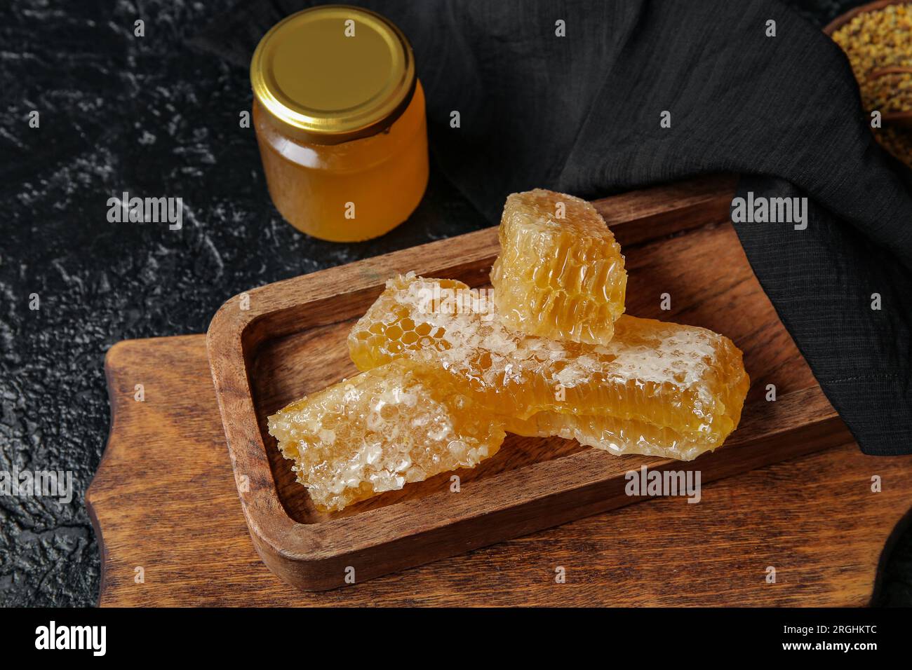 Jar of honey and board with combs on dark background, closeup Stock ...
