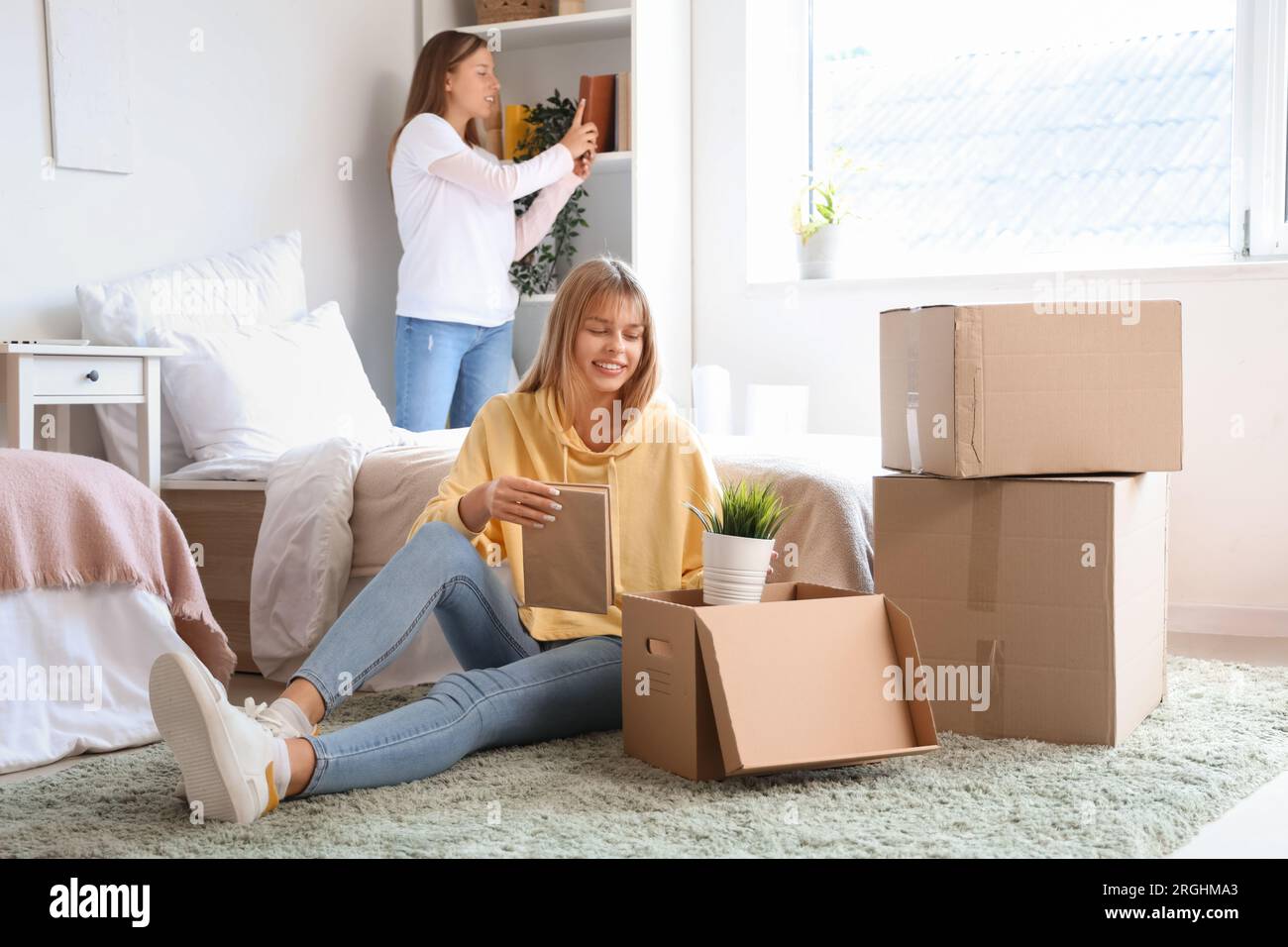 Female student unpacking things in dorm room on moving day Stock Photo ...