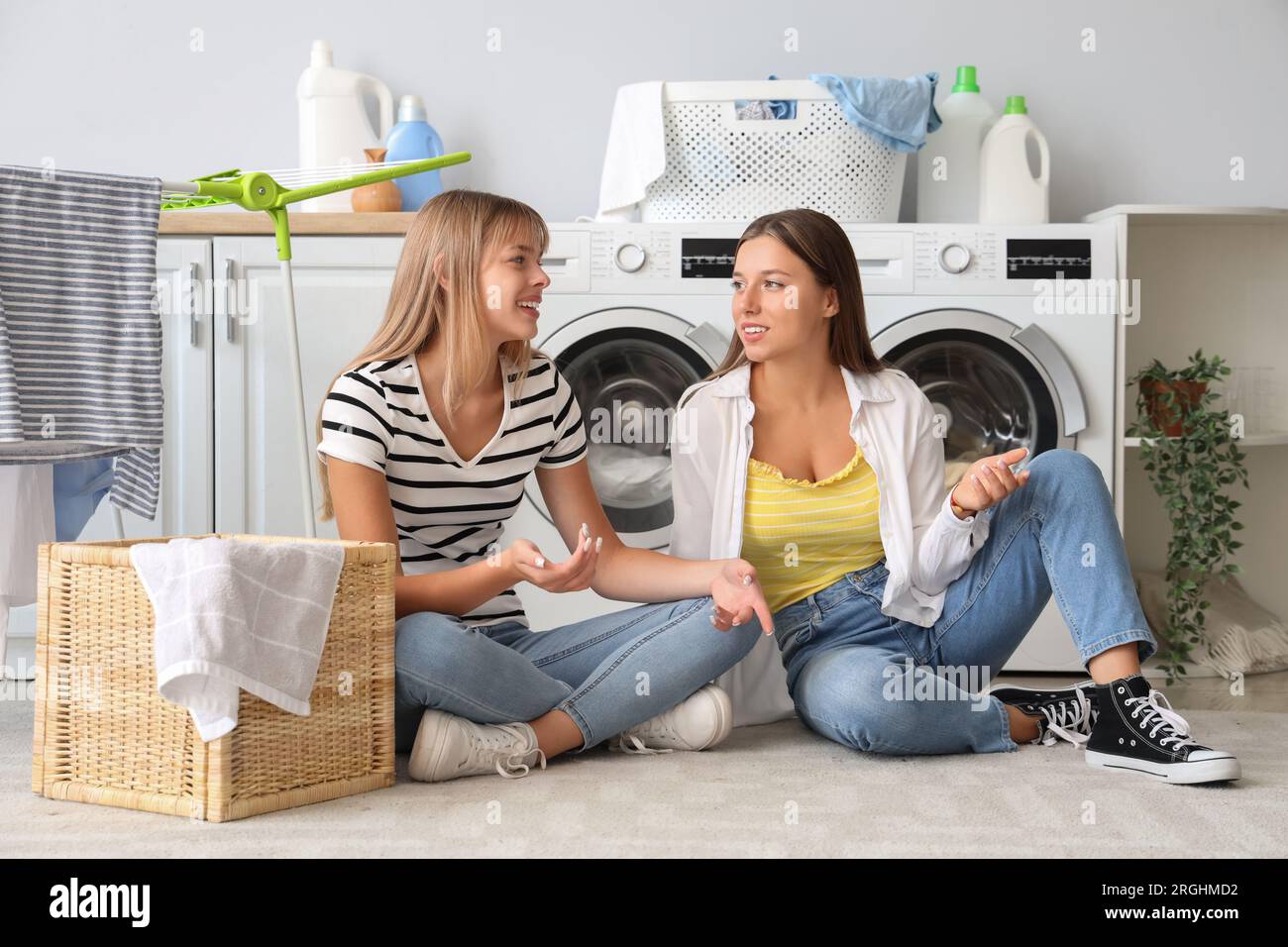 Female students sitting in dorm laundry room Stock Photo - Alamy
