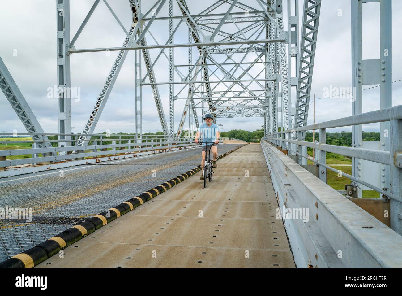 senior man is riding a folding bike over Chain of Rocks Canal Bridge ...