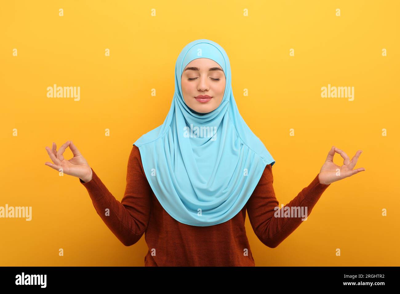 Muslim woman in hijab meditating on orange background Stock Photo - Alamy