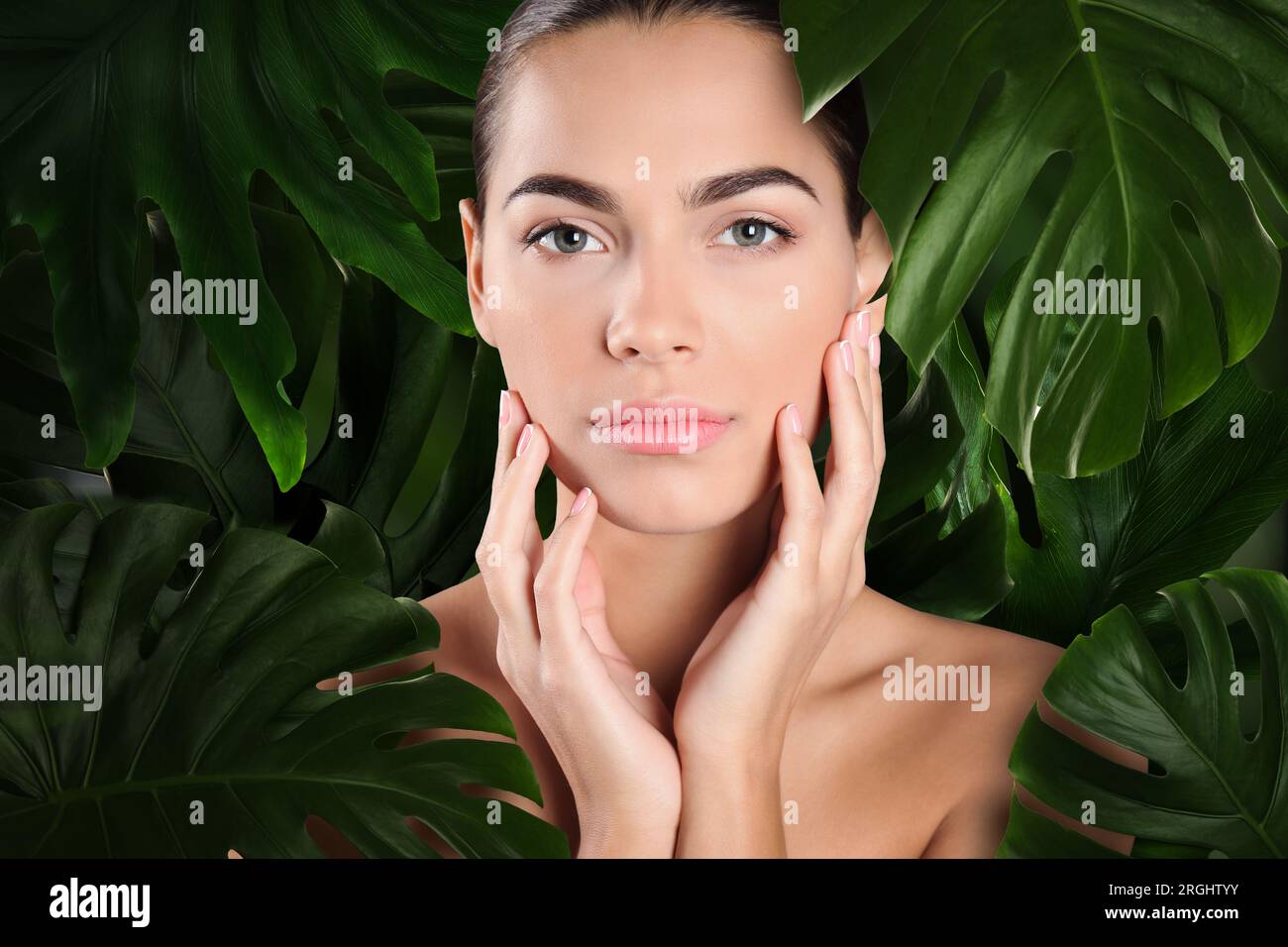 Beautiful young woman surrounded by green leaves feeling harmony while ...