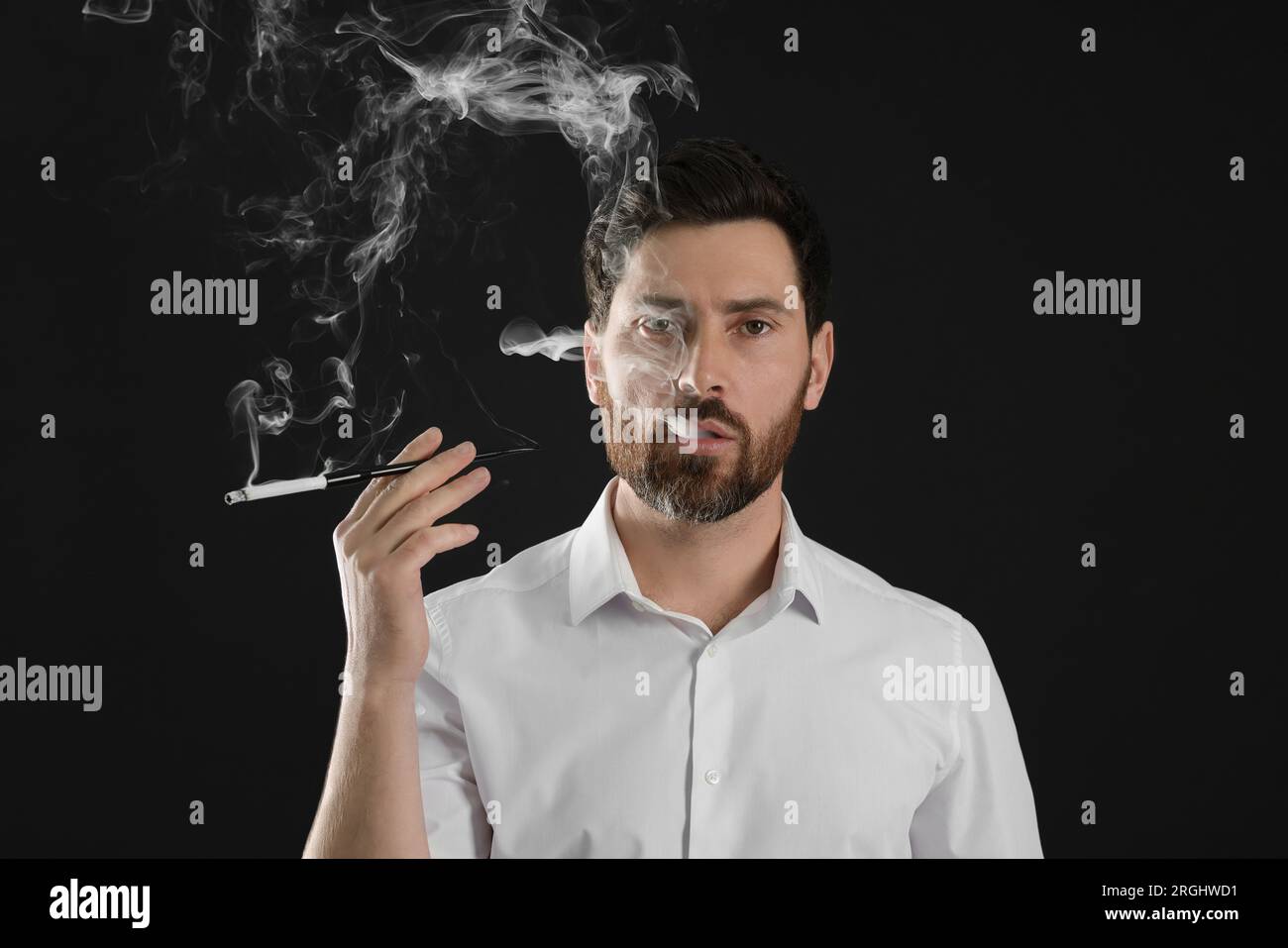 Man using long cigarette holder for smoking on black background Stock ...