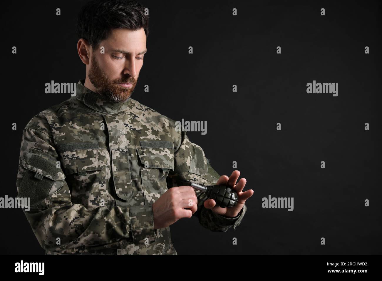 Soldier pulling safety pin out of hand grenade on black background ...
