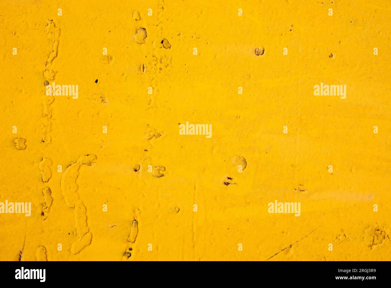 Yellow paint deteriorating from metal surface, indicating aging and ...