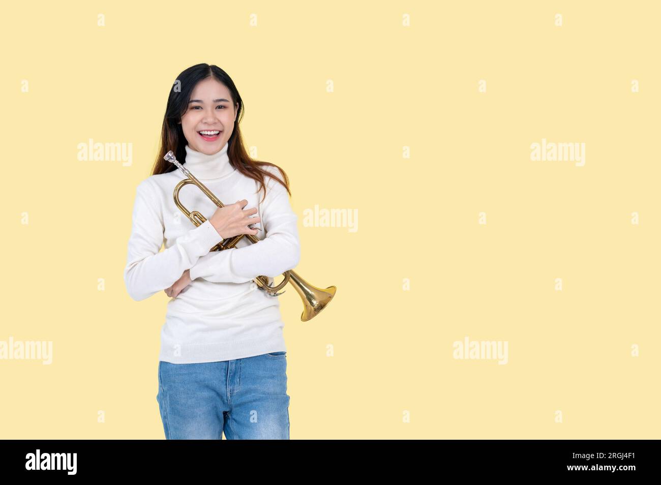 A pretty and talented Asian woman is holding the trumpet while standing ...