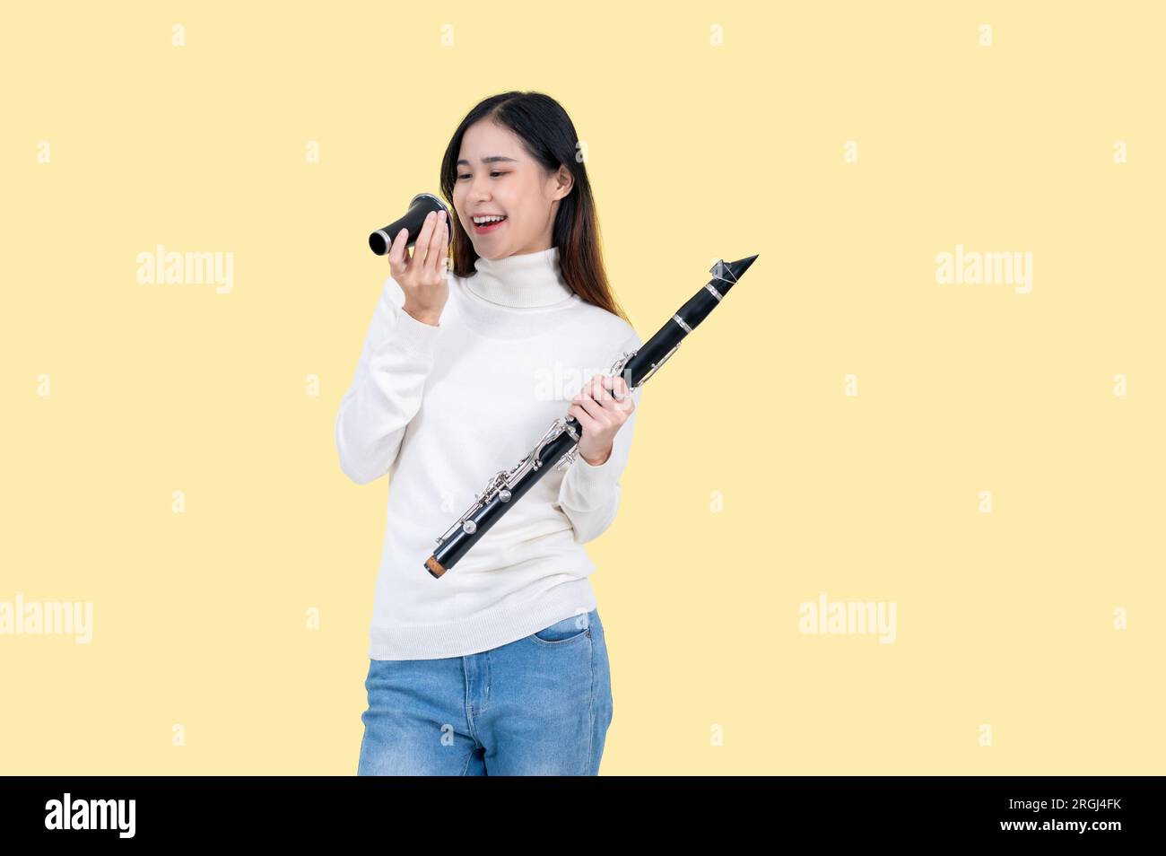A beautiful Asian woman holding a clarinet while standing against an ...