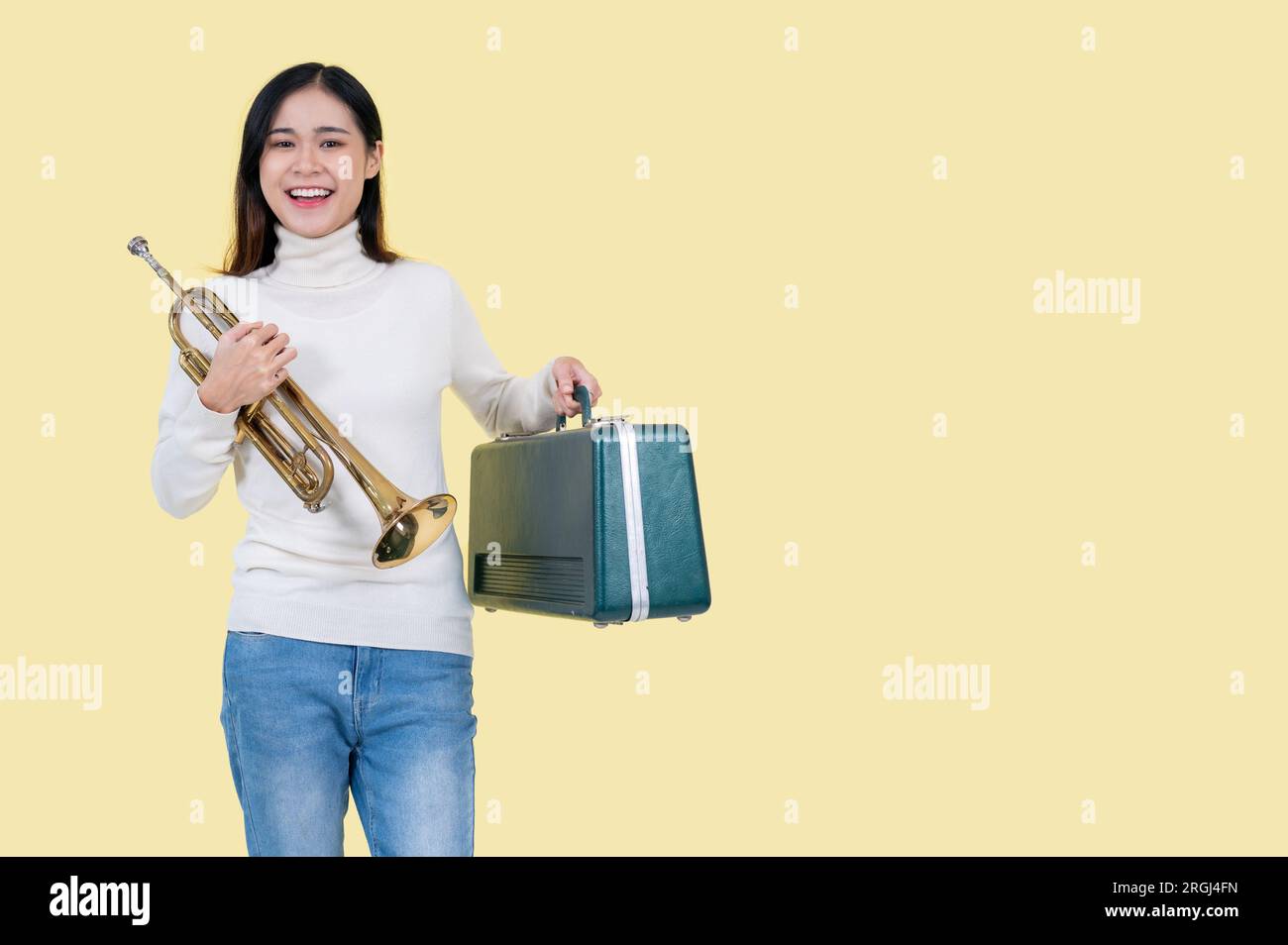 A beautiful Asian woman is holding the trumpet while standing against ...