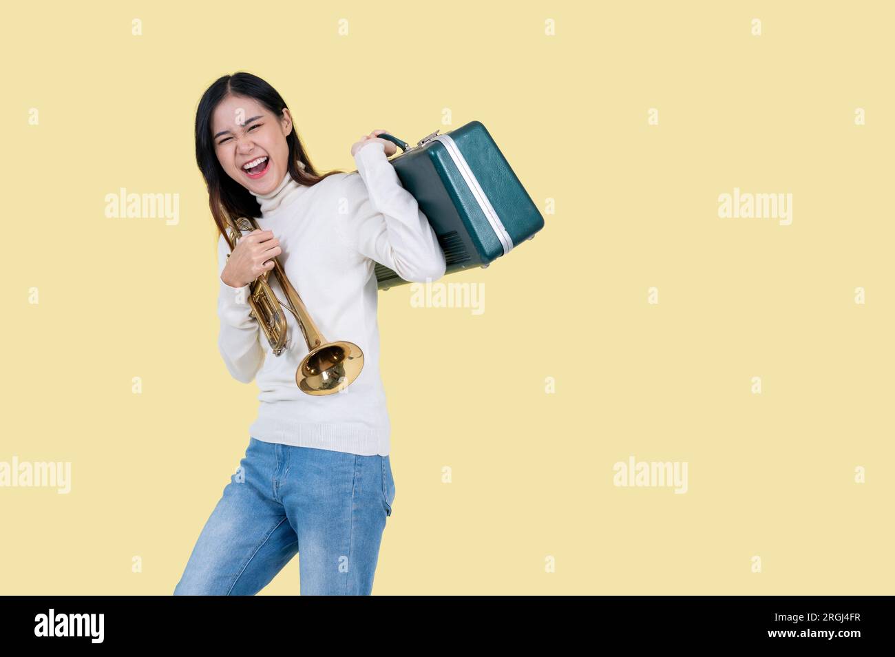 A cheerful and talented Asian woman is holding the trumpet while ...